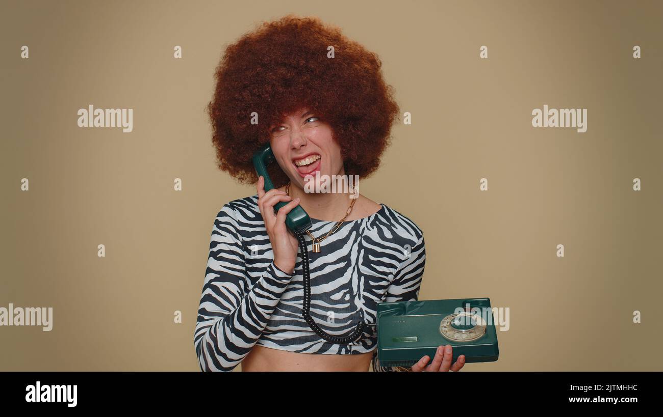 Crazy pretty young woman with brown lush wig talking on wired vintage ...