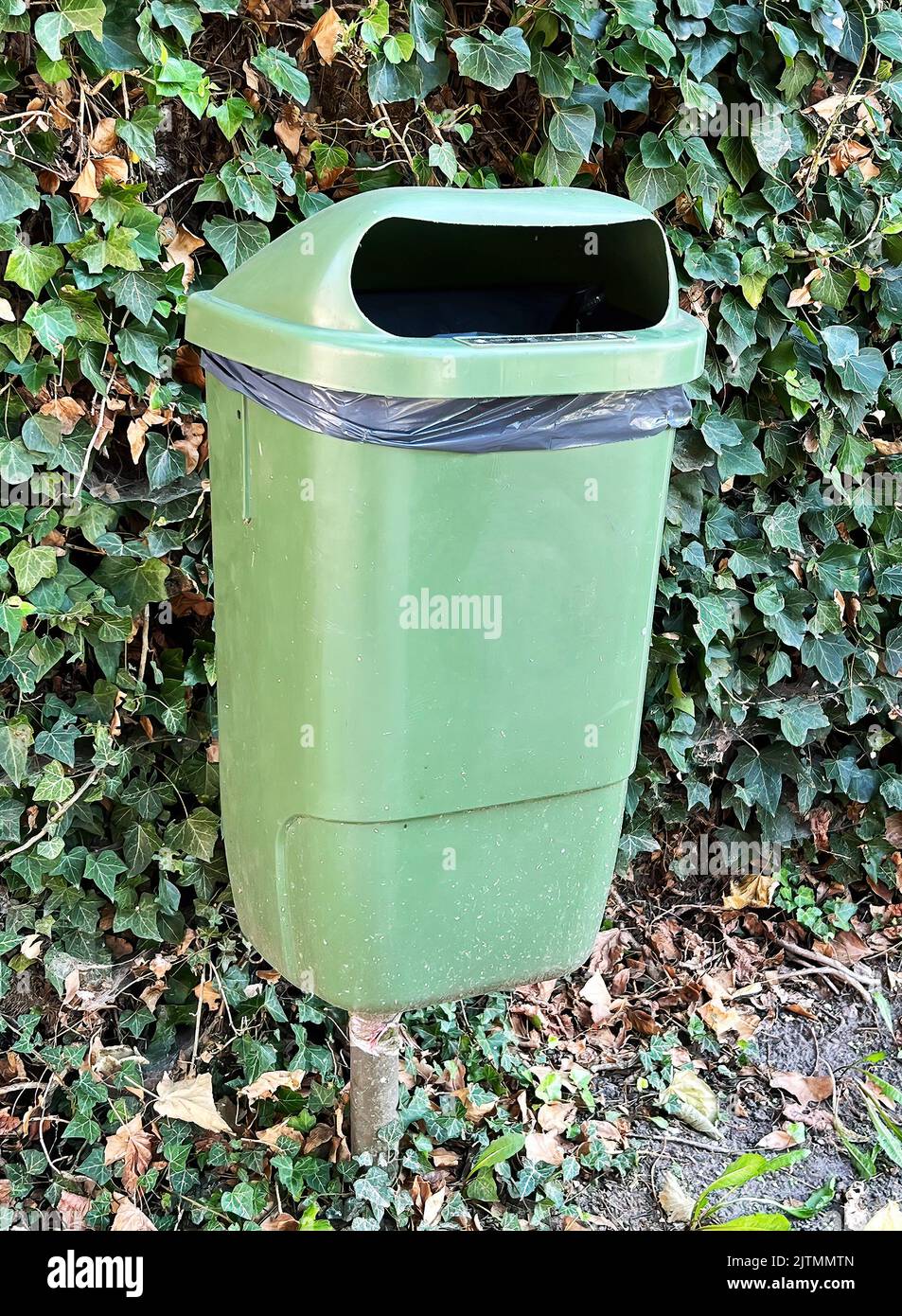 Vertical shot on a green plastic public wastebasket for disposal of ...