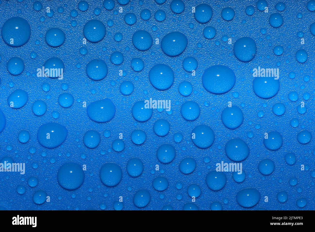 Water droplets on a shiny blue plastic surface giving a fresh, vibrant ...