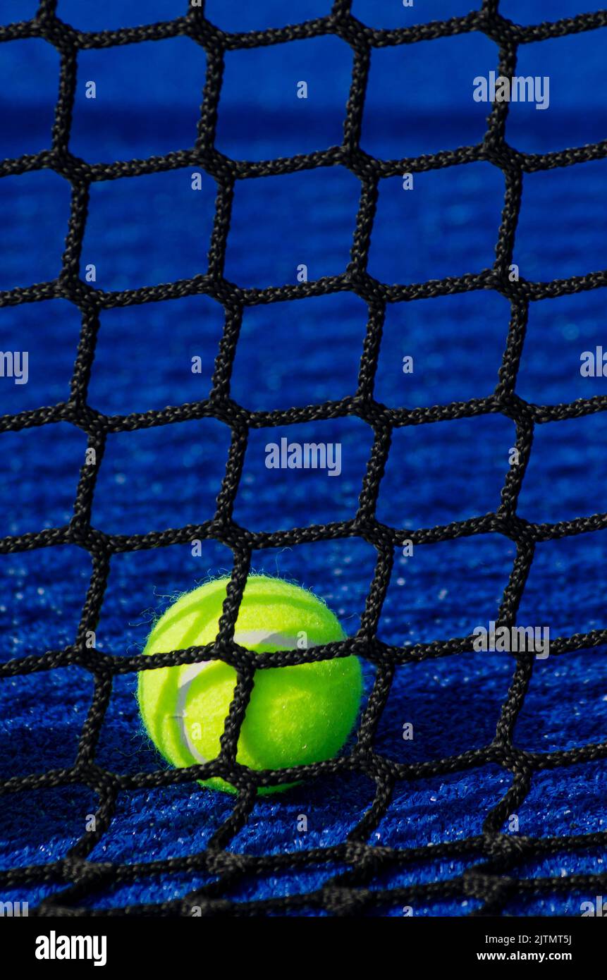 A vertical shot of a tennis ball behind the net on a blue tennis court ...
