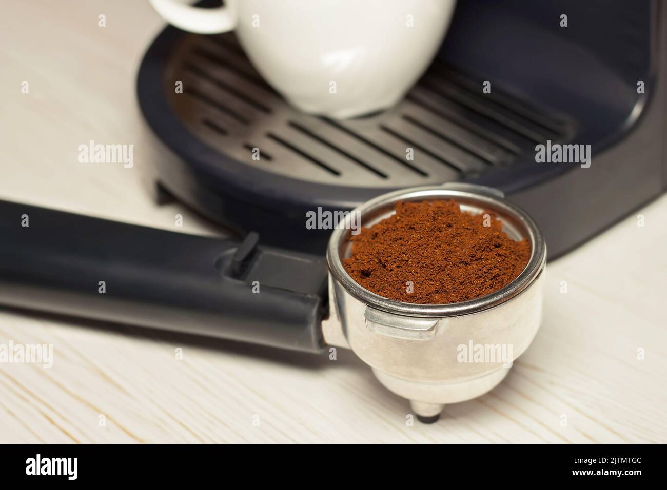 Coffee machine filter holder with ground and cup of coffee on white ...