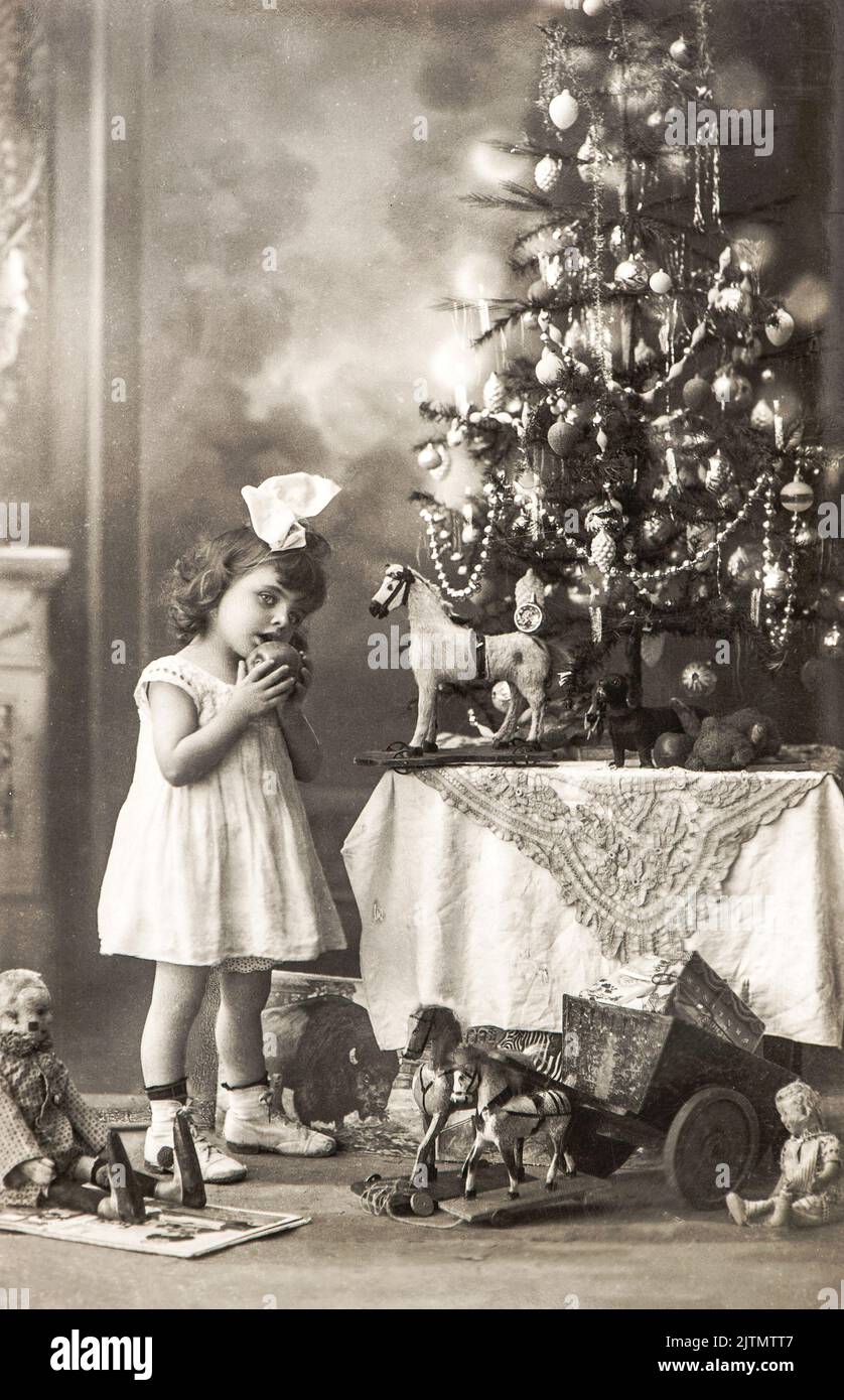 Baby girl with Christmas tree and vintage toys, circa 1900 Germany. Old ...