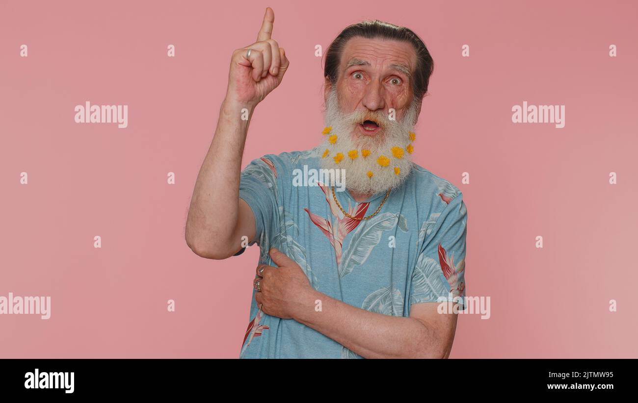 Eureka. Inspired senior man 60s in t-shirt pointing finger up with open ...
