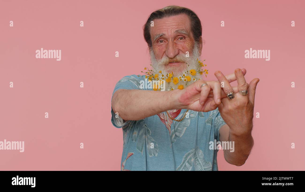 Cheerful senior man with flowers in beard showing hashtag symbol with ...