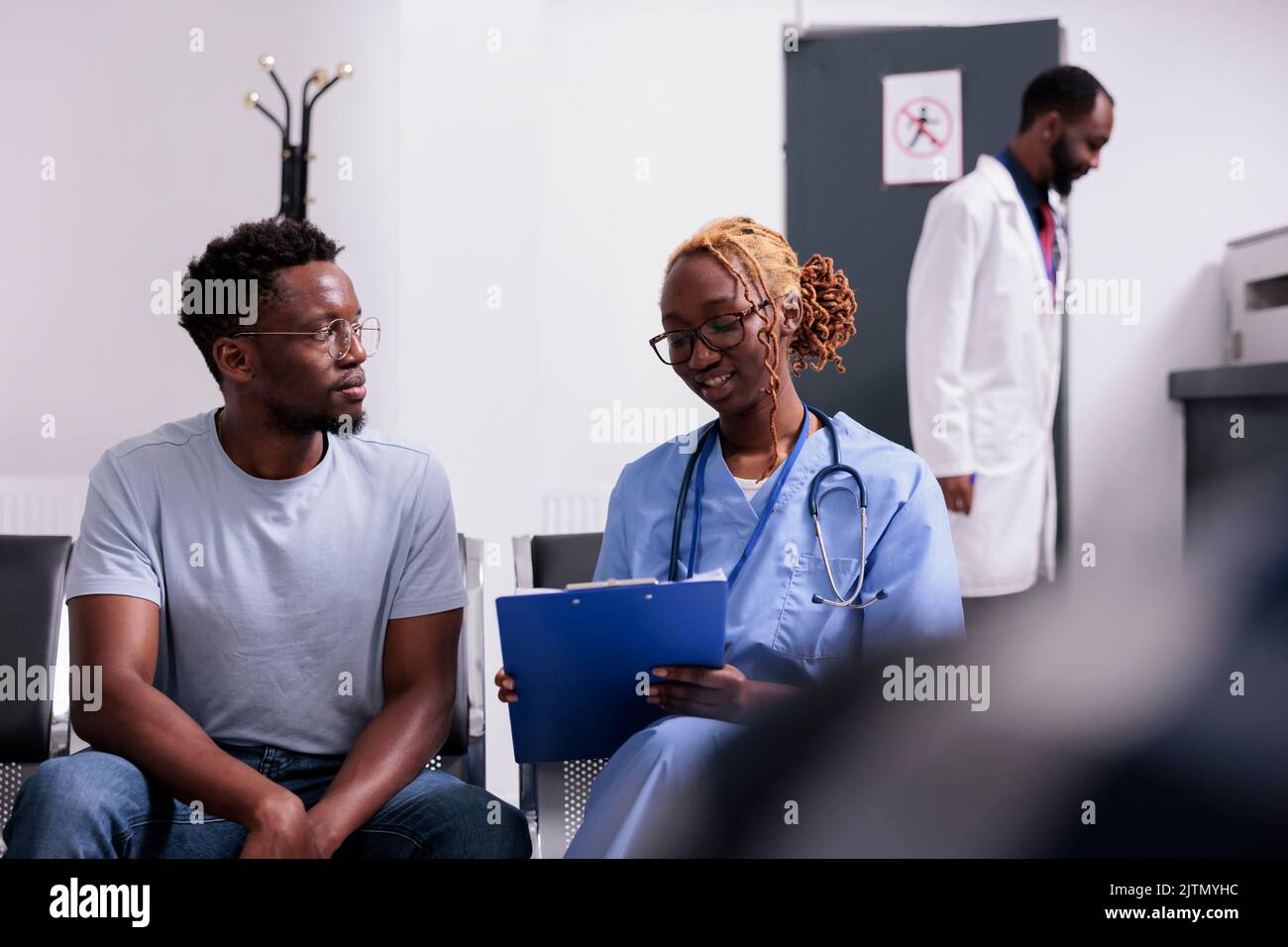 Health specialist examining young man in waiting area lobby, taking ...