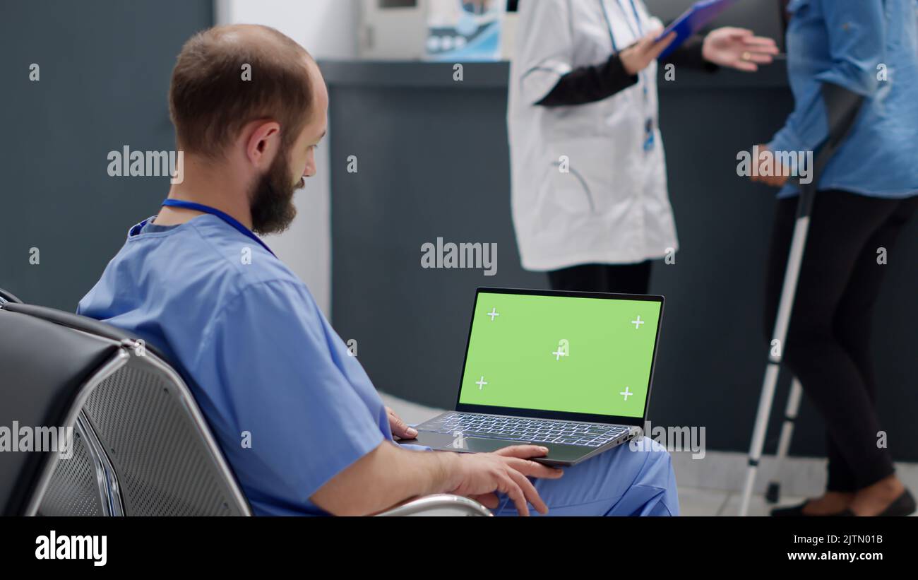 Medical assistant working on laptop with greenscreen in reception lobby ...