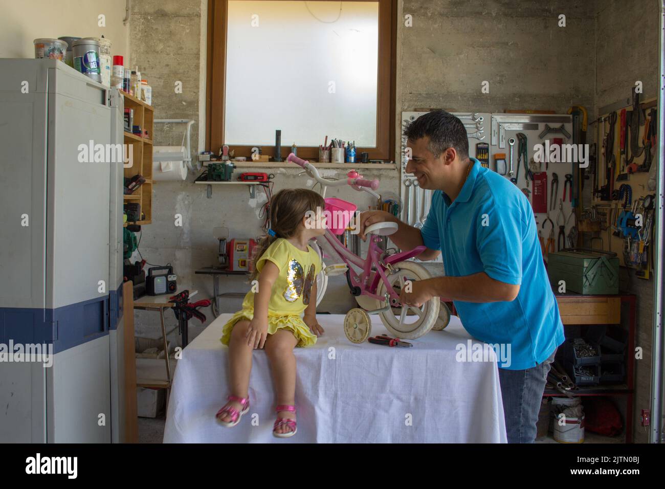 Image of a dad with his daughter in the garage at home as they repair ...