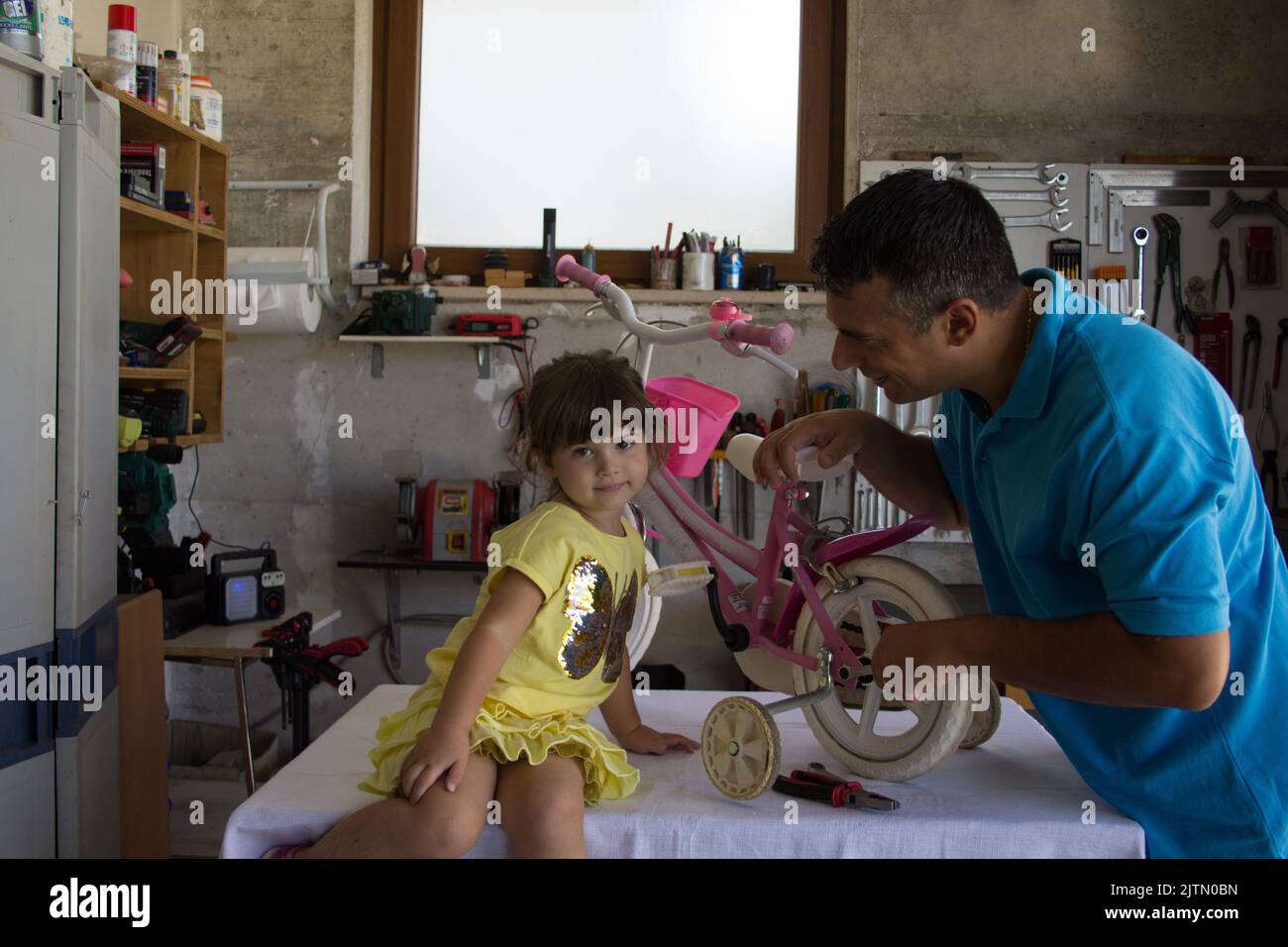 Image of a dad with his daughter in the garage at home as they repair ...