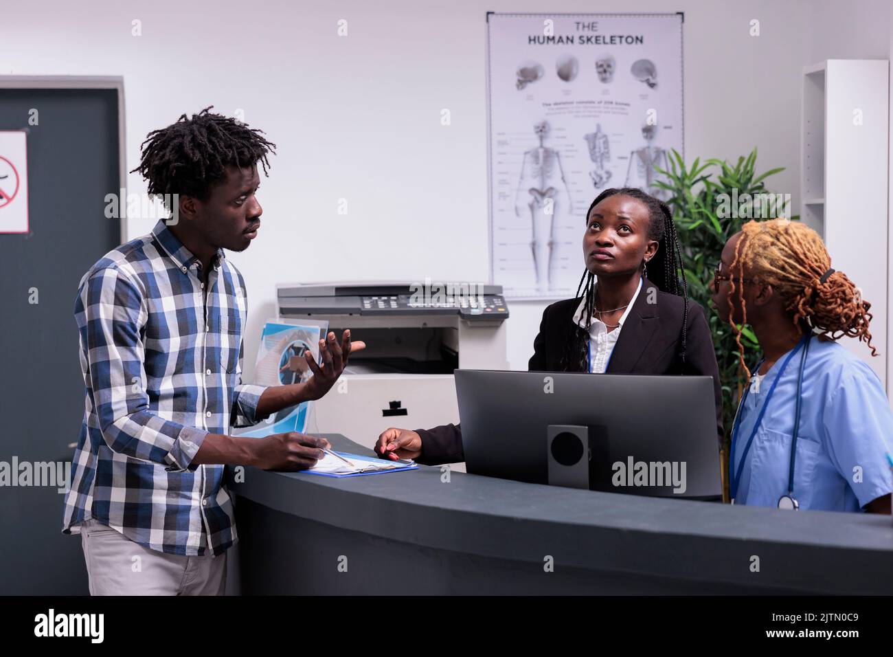 African american medical staff talking to patient at hospital reception ...