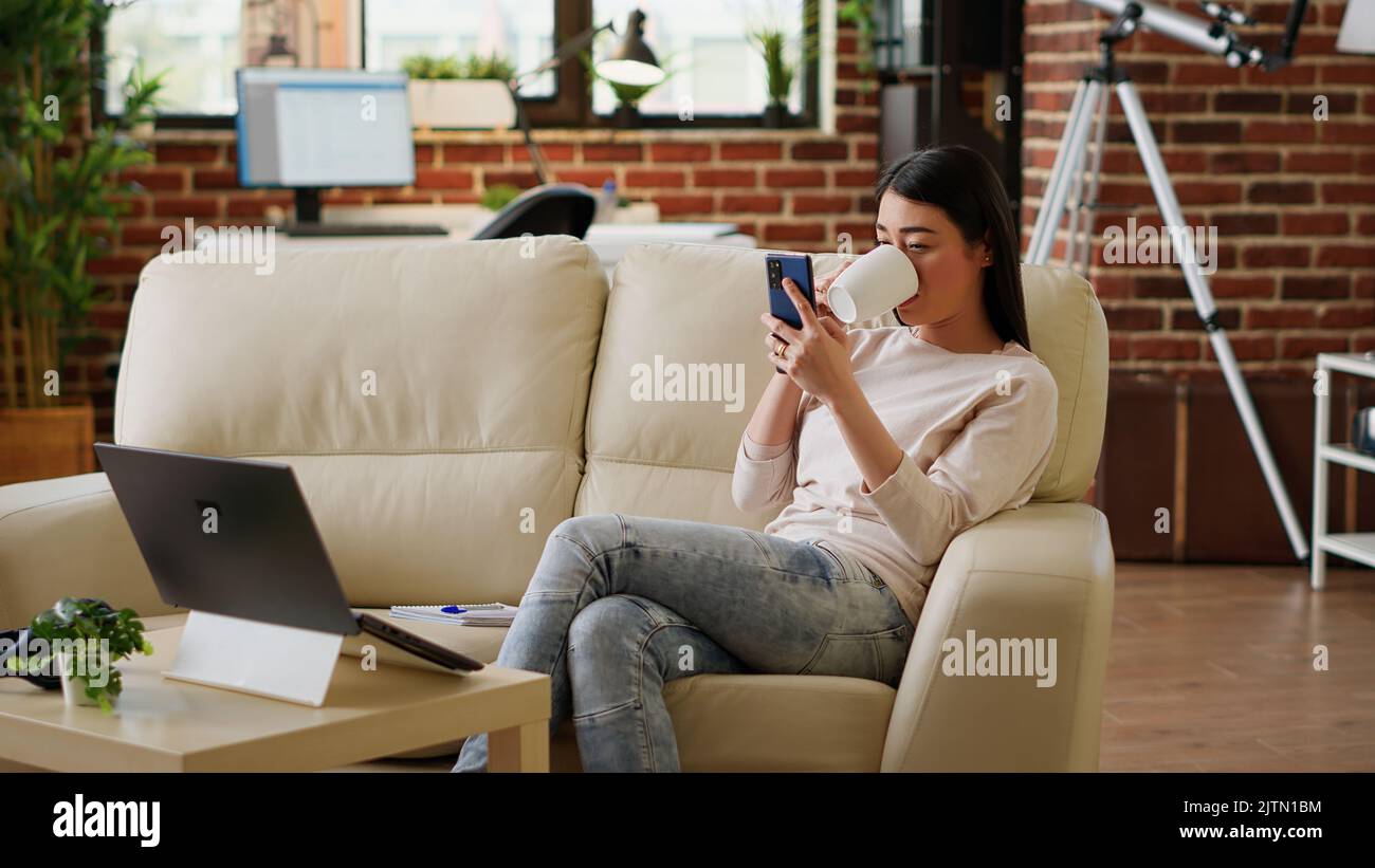 Happy woman sending messages on mobile phone while doing work from home ...