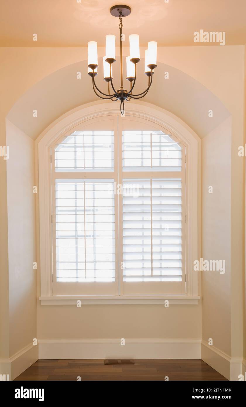 Chandelier and arched window in bedroom with creamy white painted wall ...