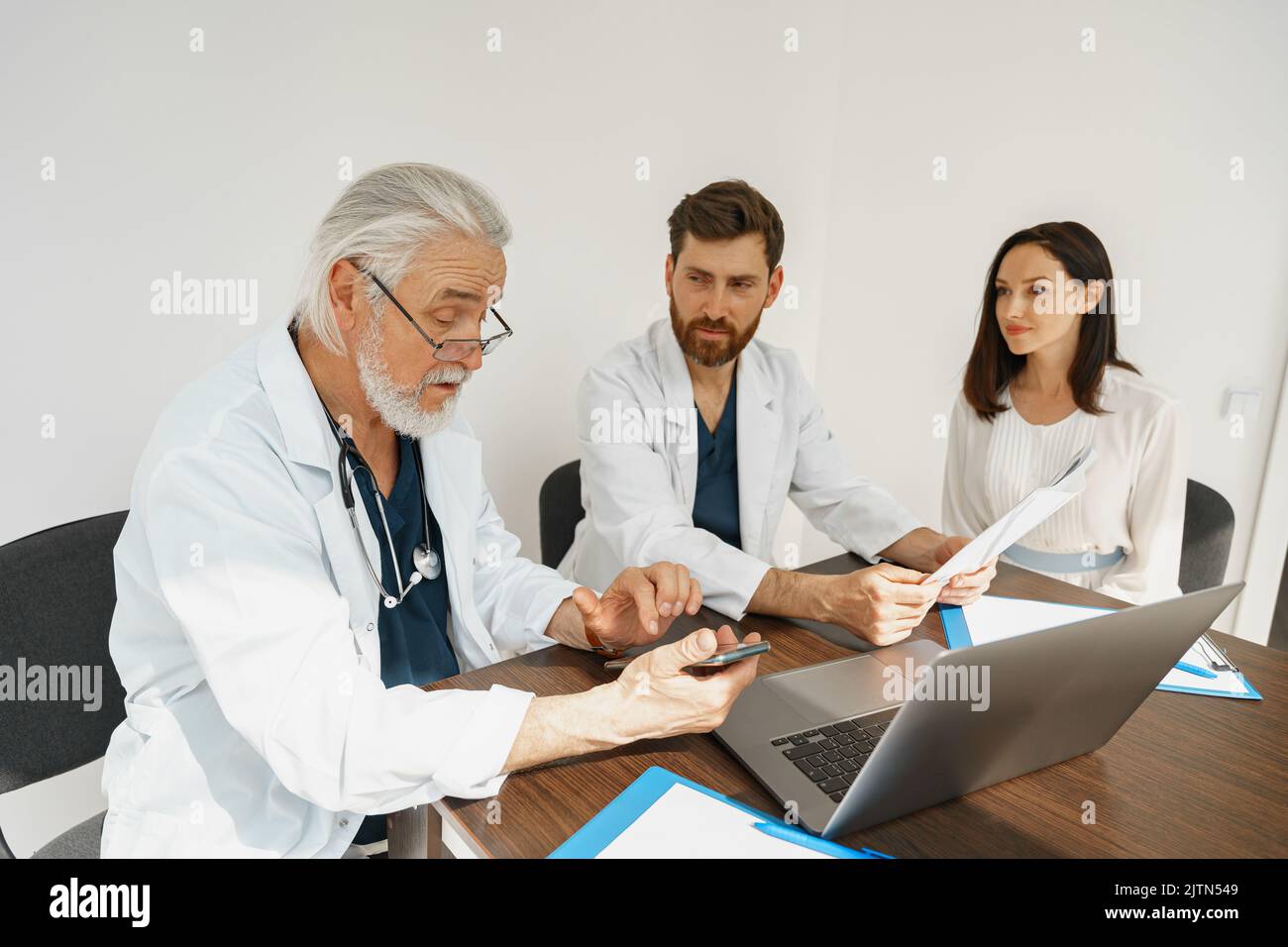 Two doctors in white uniform consult female patient at meeting in ...
