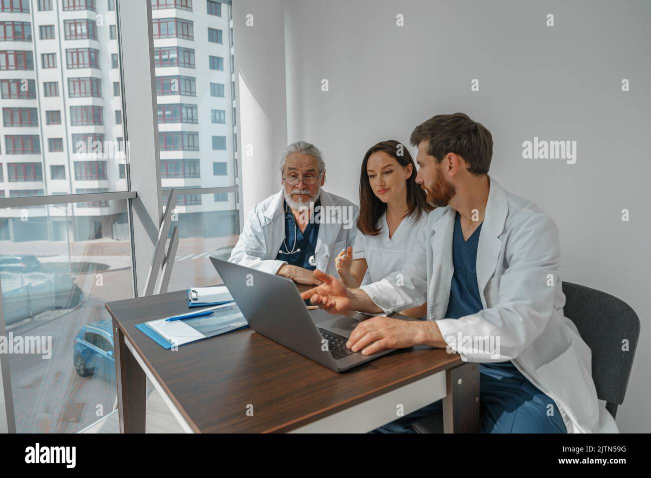 Group of doctors sitting at meeting table in conference room during ...