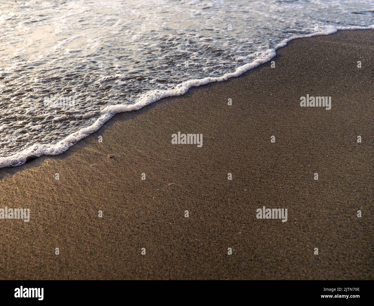 Wet sand of the beach in the rays of the setting sun. The silence of ...