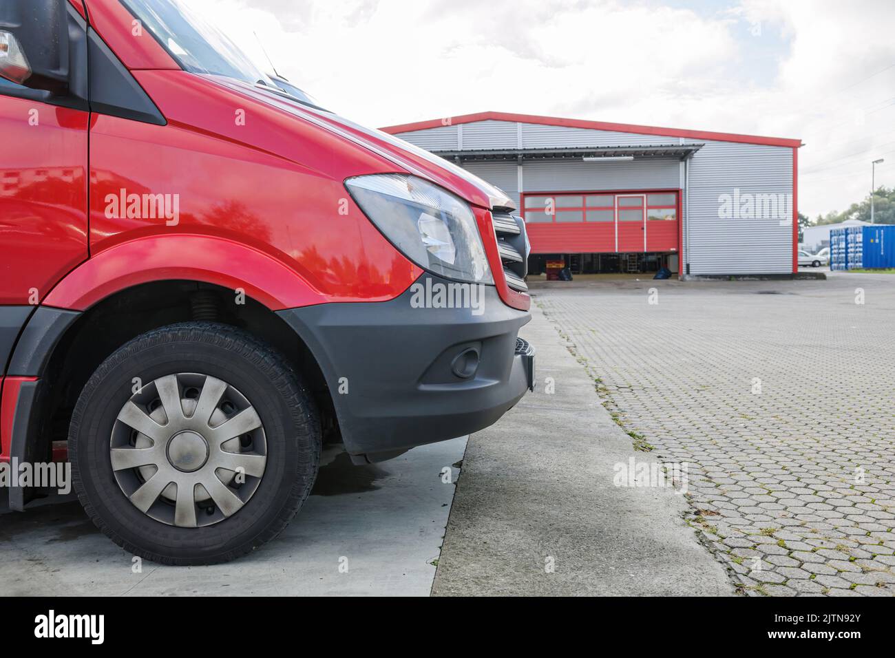 Front part of a red delivery van in front of logistics warehouse center ...