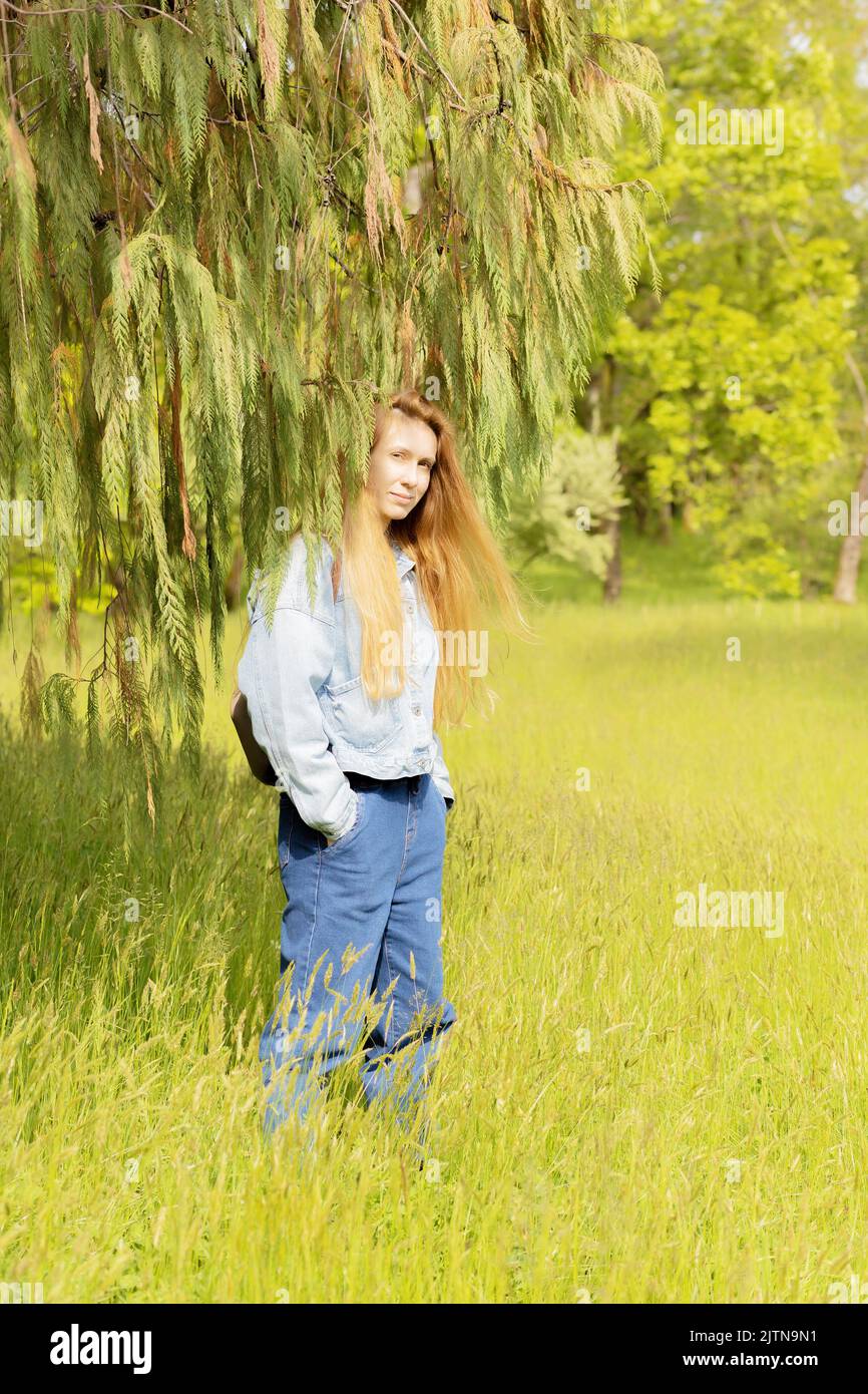 Woman in a meadow under branches of a tree. Woman in the park under a ...