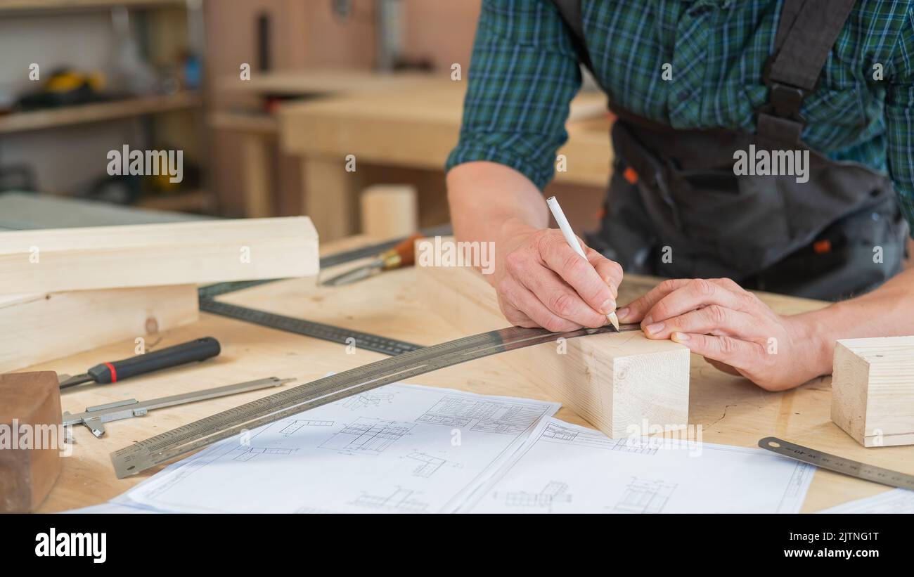A carpenter measures wooden planks and makes marks with a pencil in a ...