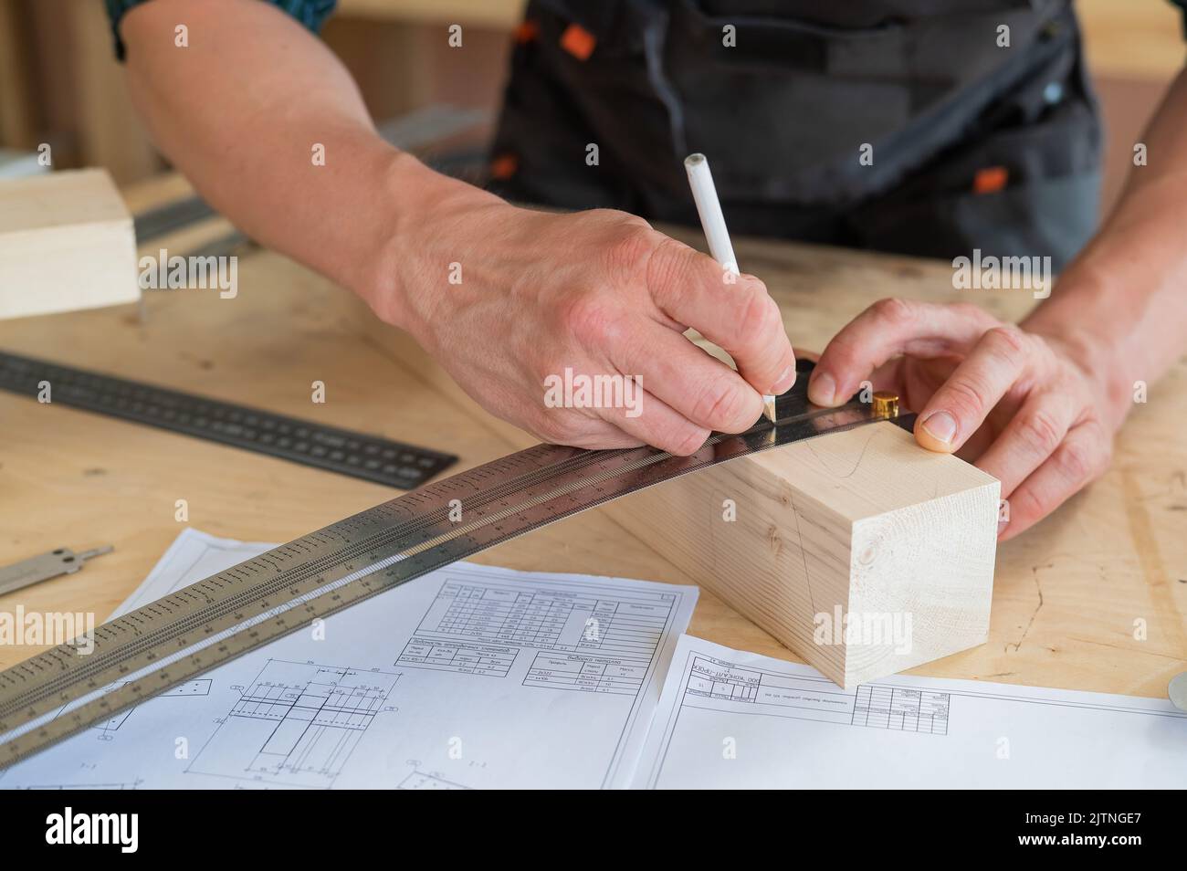 A carpenter measures wooden planks and makes marks with a pencil in a ...