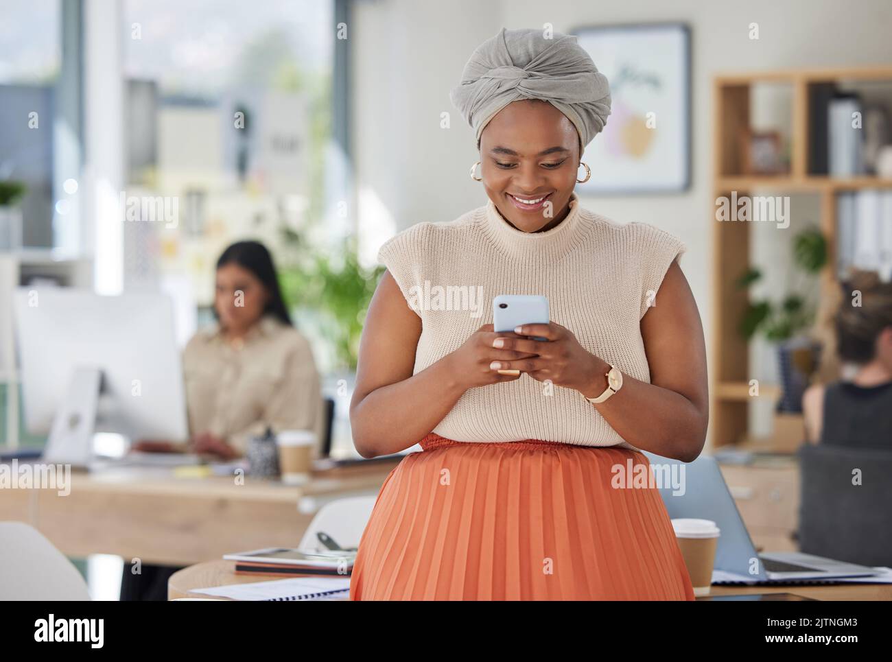 Black business woman texting on a phone, smiling while standing in a ...