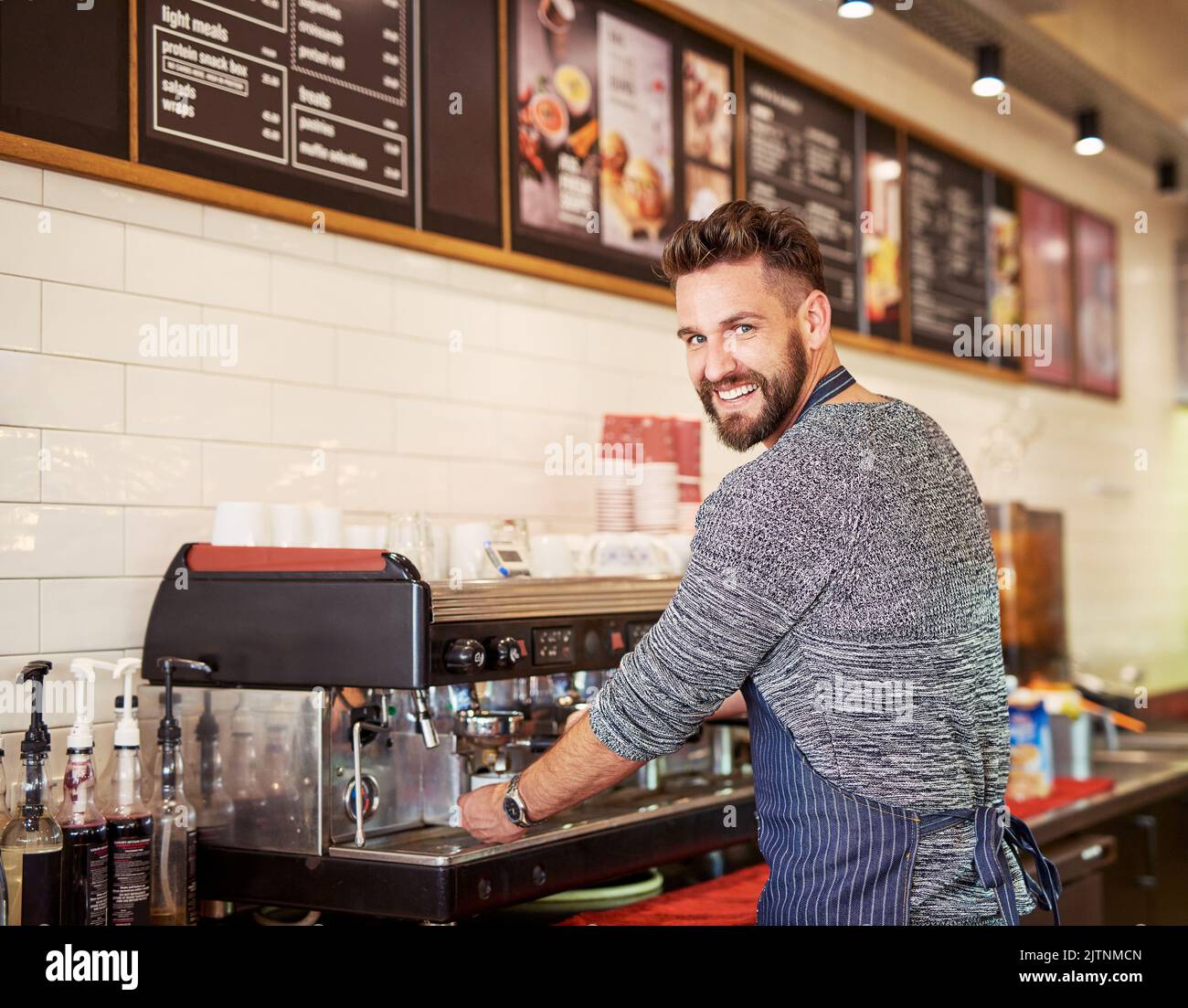 I only brew the best. Portrait of a barista operating a coffee machine ...