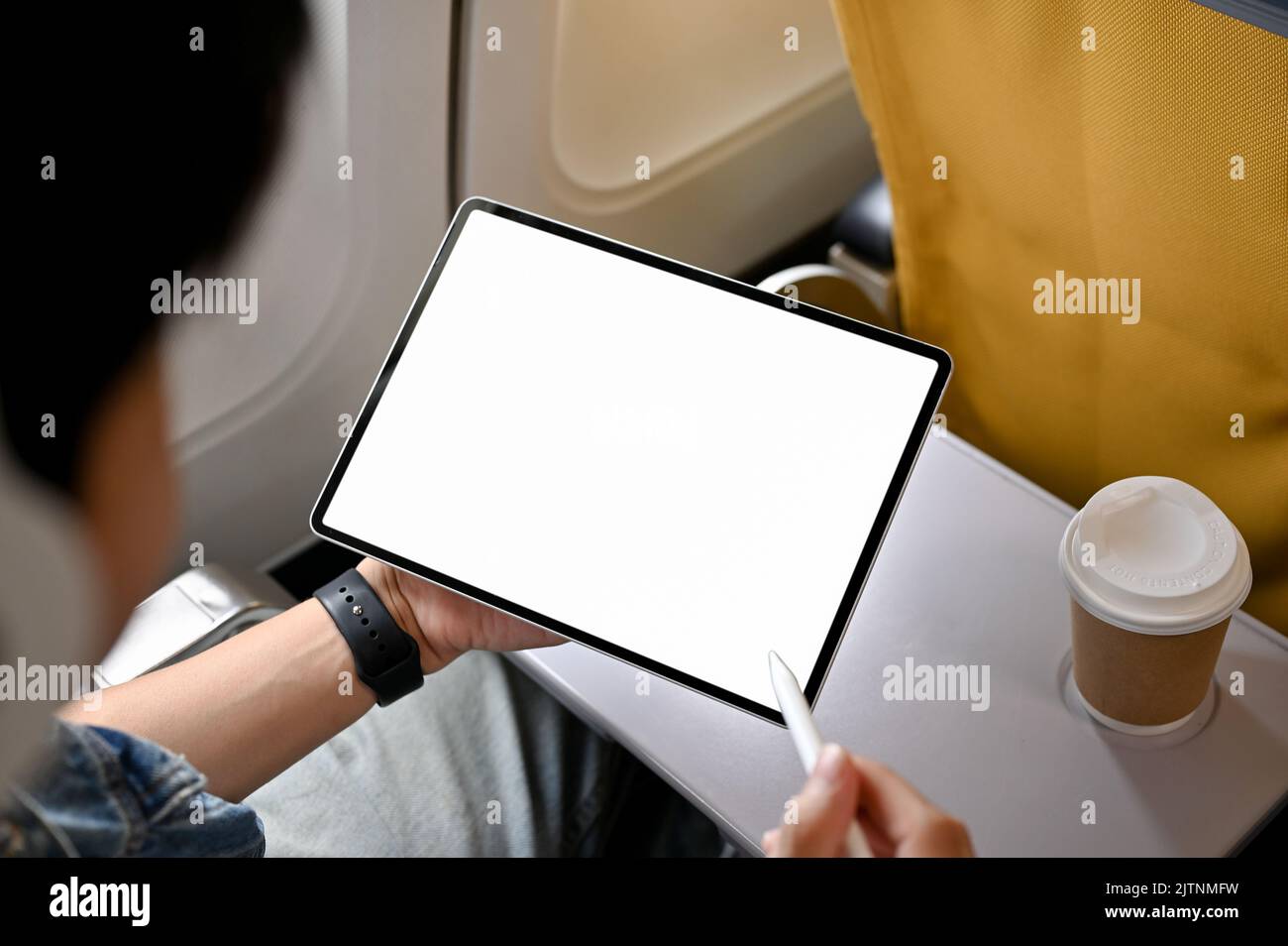 Male traveler or passenger sits at the window seat, using his portable ...