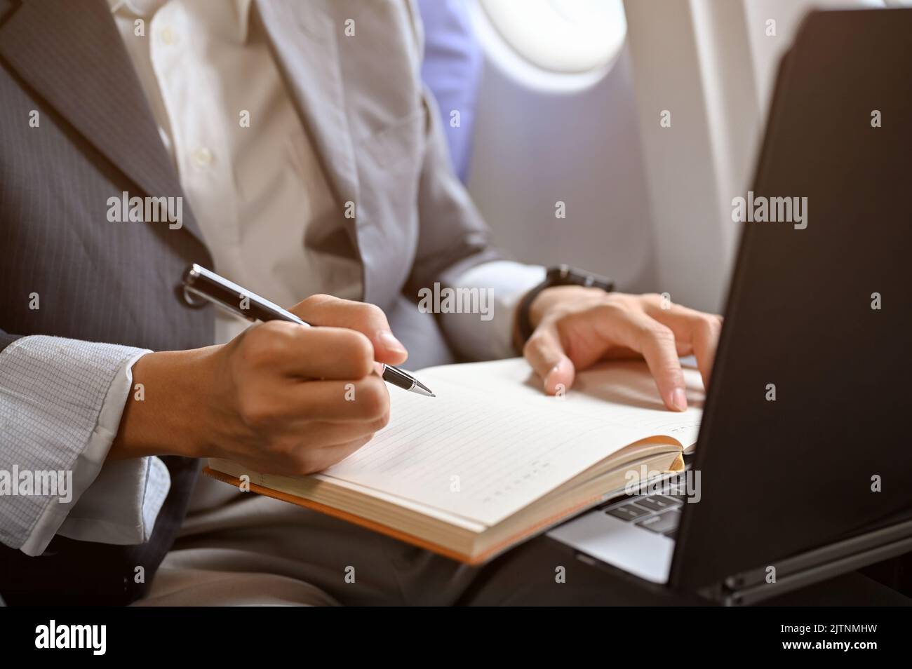 A businessman taking notes on his notebook, using laptop computer ...