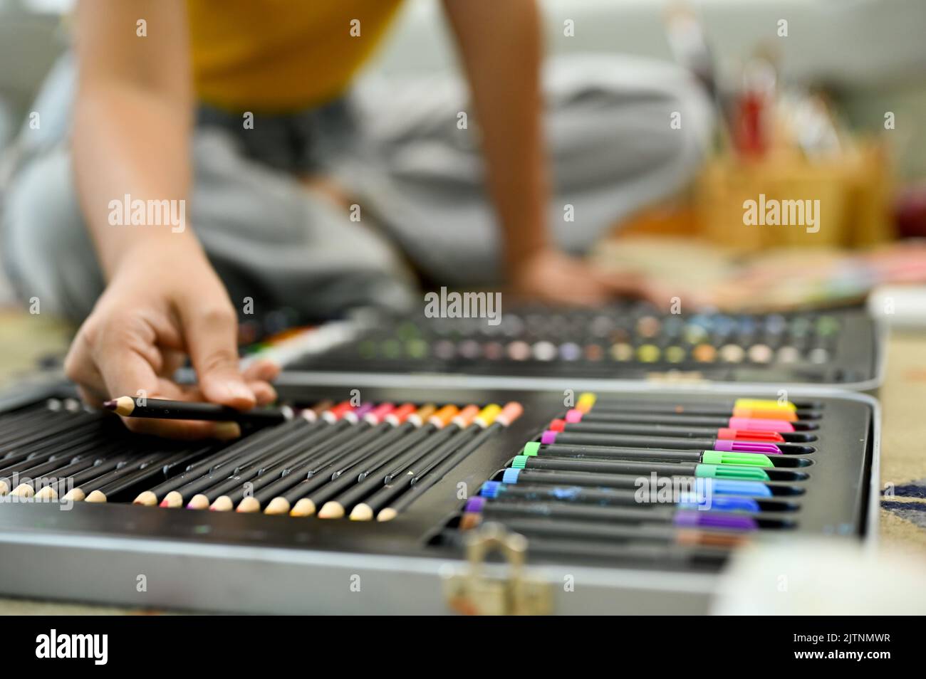 A female student choosing a pencil color for her artwork from a ...