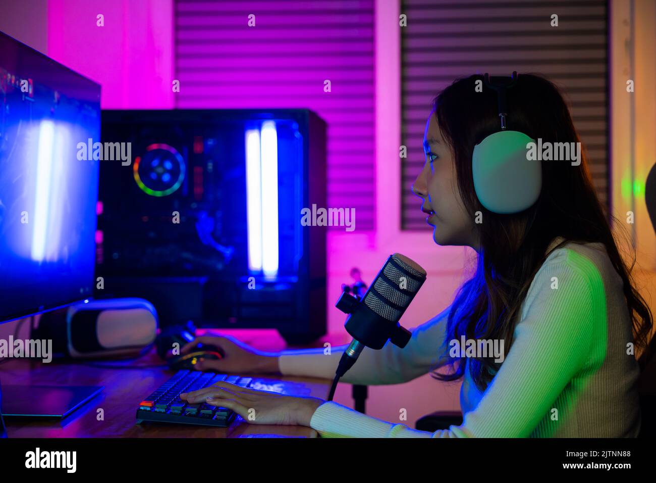 Asian young gamer woman wear headphones playing video games online on ...