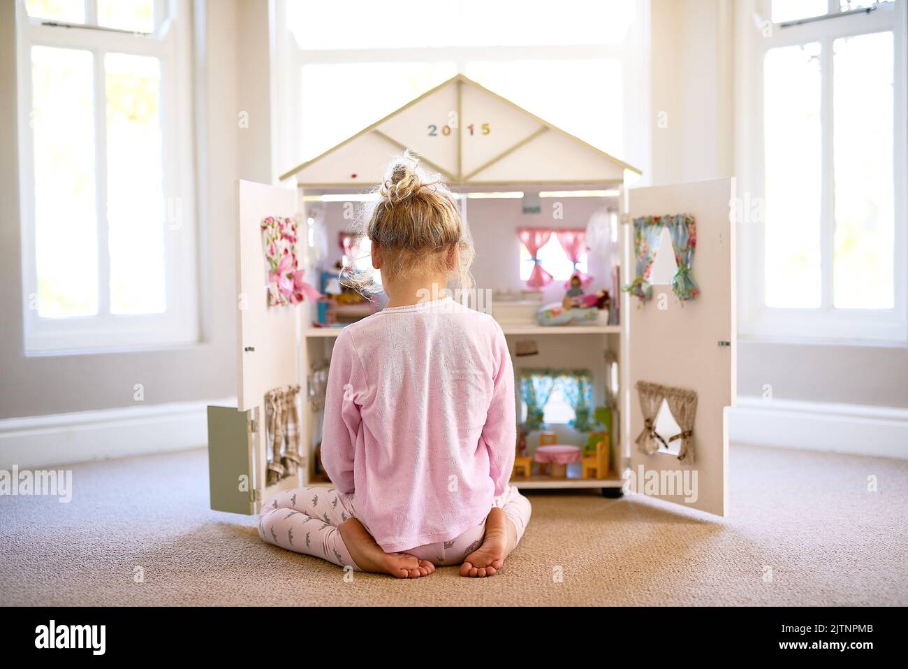 Having fun in fantasy. a little girl playing with her dollhouse at home ...