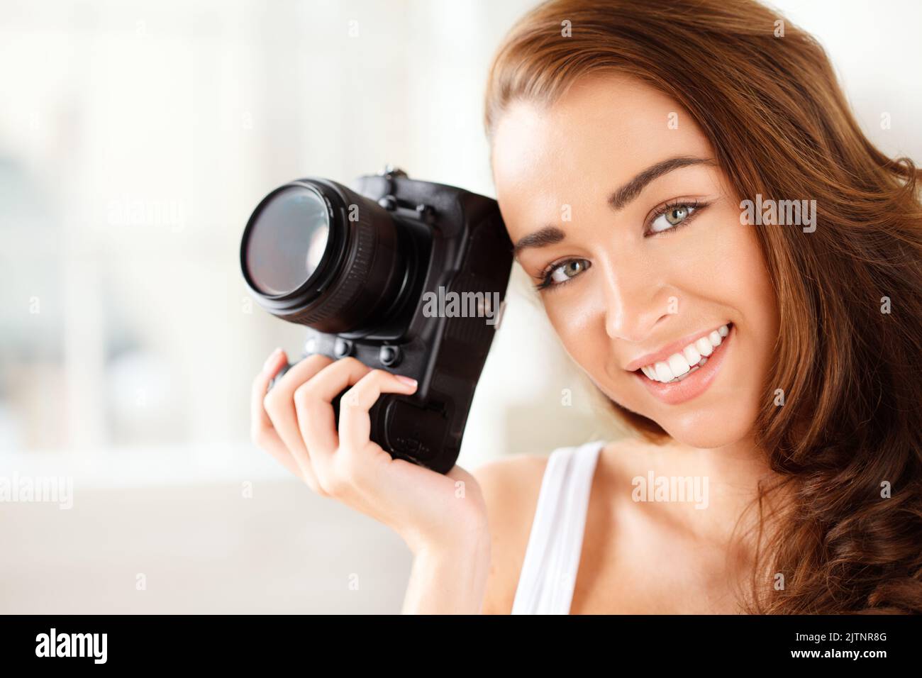 Portrait of happy woman photographer working in model studio doing photoshoot with camera ...