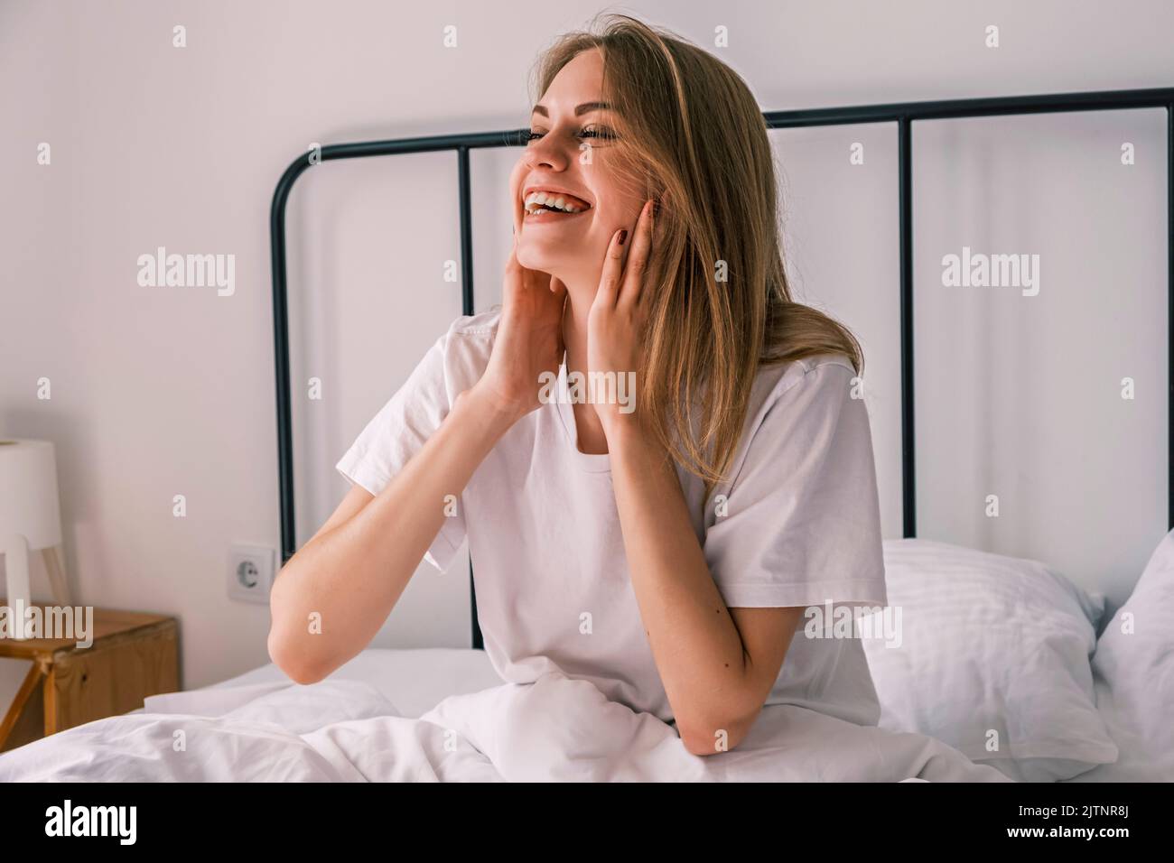 Waking up in the morning. Young happy woman smiling and touching her ...