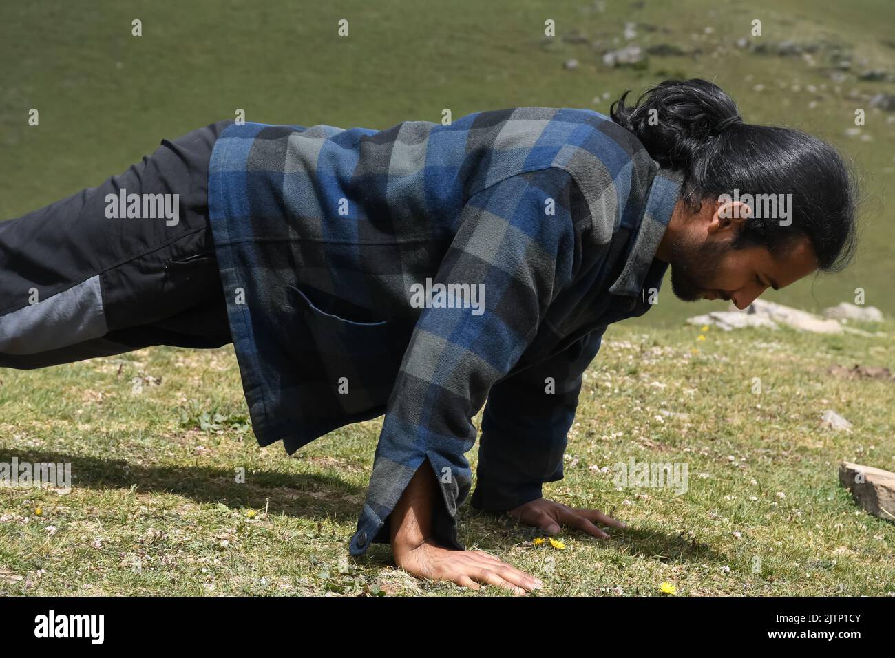 Side view of a good looking Indian young man with ponytail hair style ...