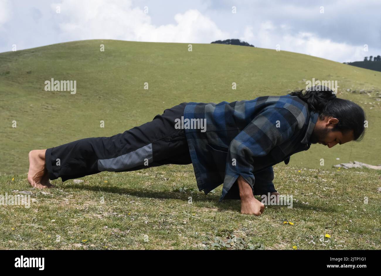 Side view of a good looking Indian young man doing fist push-ups in the ...