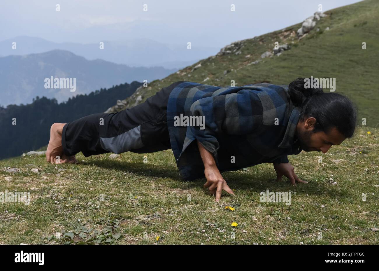 Full length of a Indian young man with ponytail hair doing three finger ...