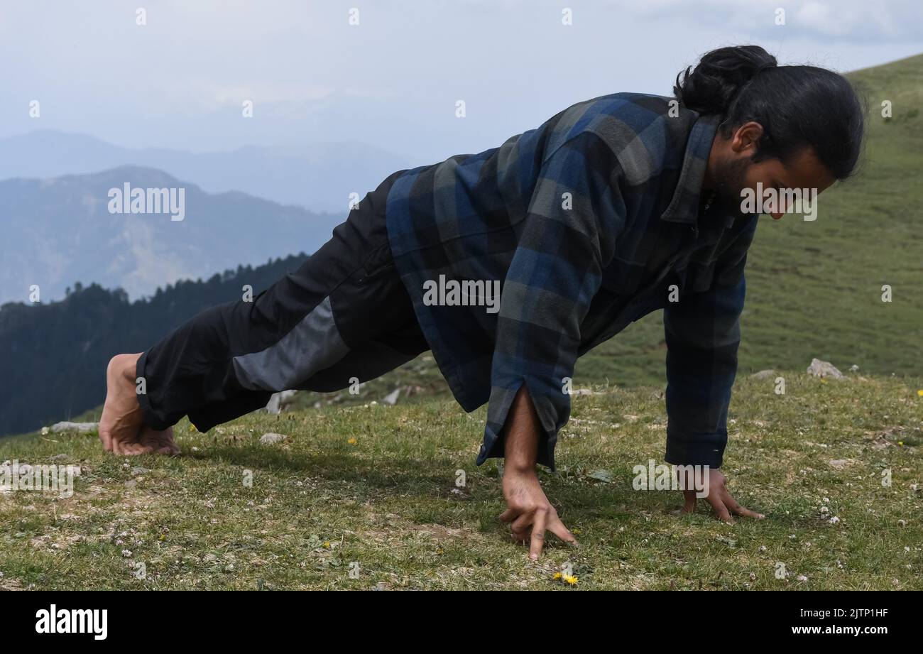Full length of a Indian young man with ponytail hair doing three finger ...