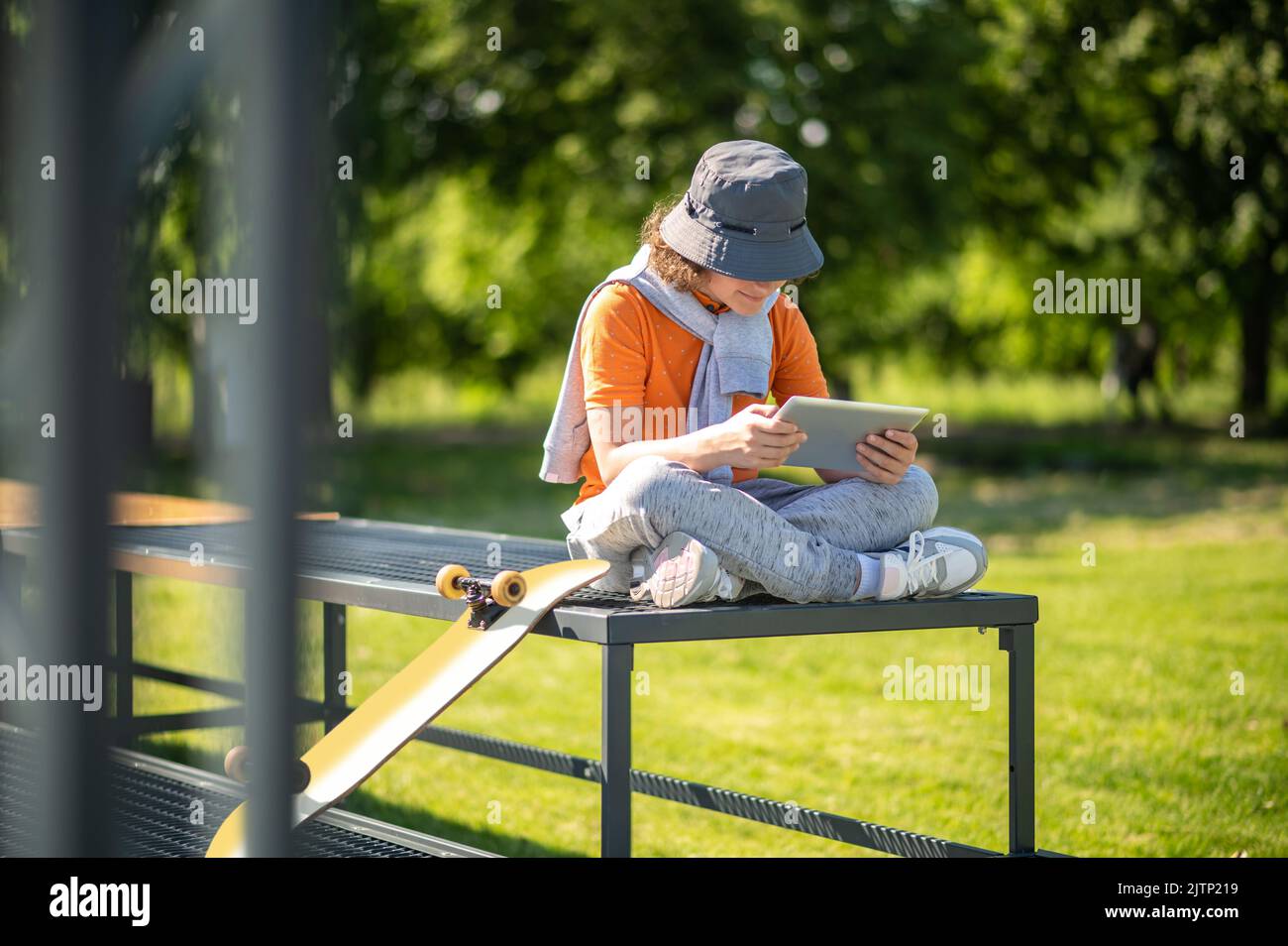 Teenage kid using his tablet computer in the park Stock Photo - Alamy