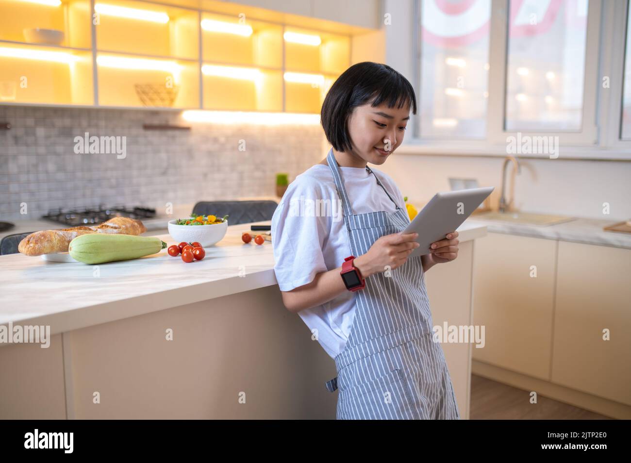 A girl in the kitchen reading a cookery blog online Stock Photo - Alamy