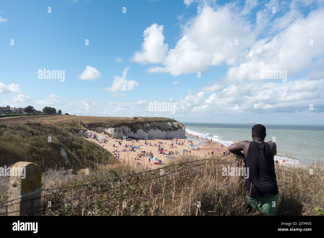 Adult dark male looking over the cliff towards the beach Stock Photo ...