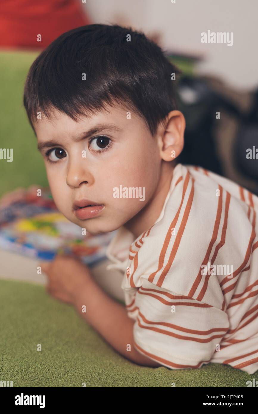 Unhappy little caucasian boy sitting on sofa at home, frustrated ...