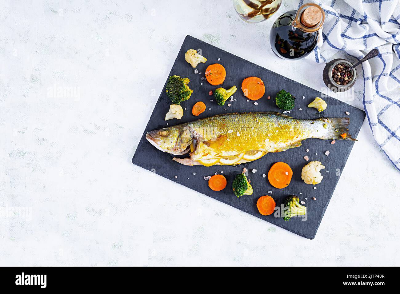 Baked sea bass fish with vegetables and greens on stone plate Stock ...