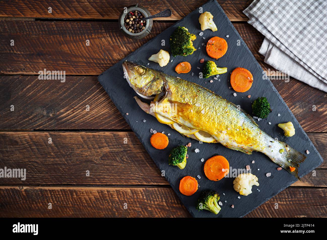 Baked sea bass fish with vegetables and greens on stone plate Stock ...