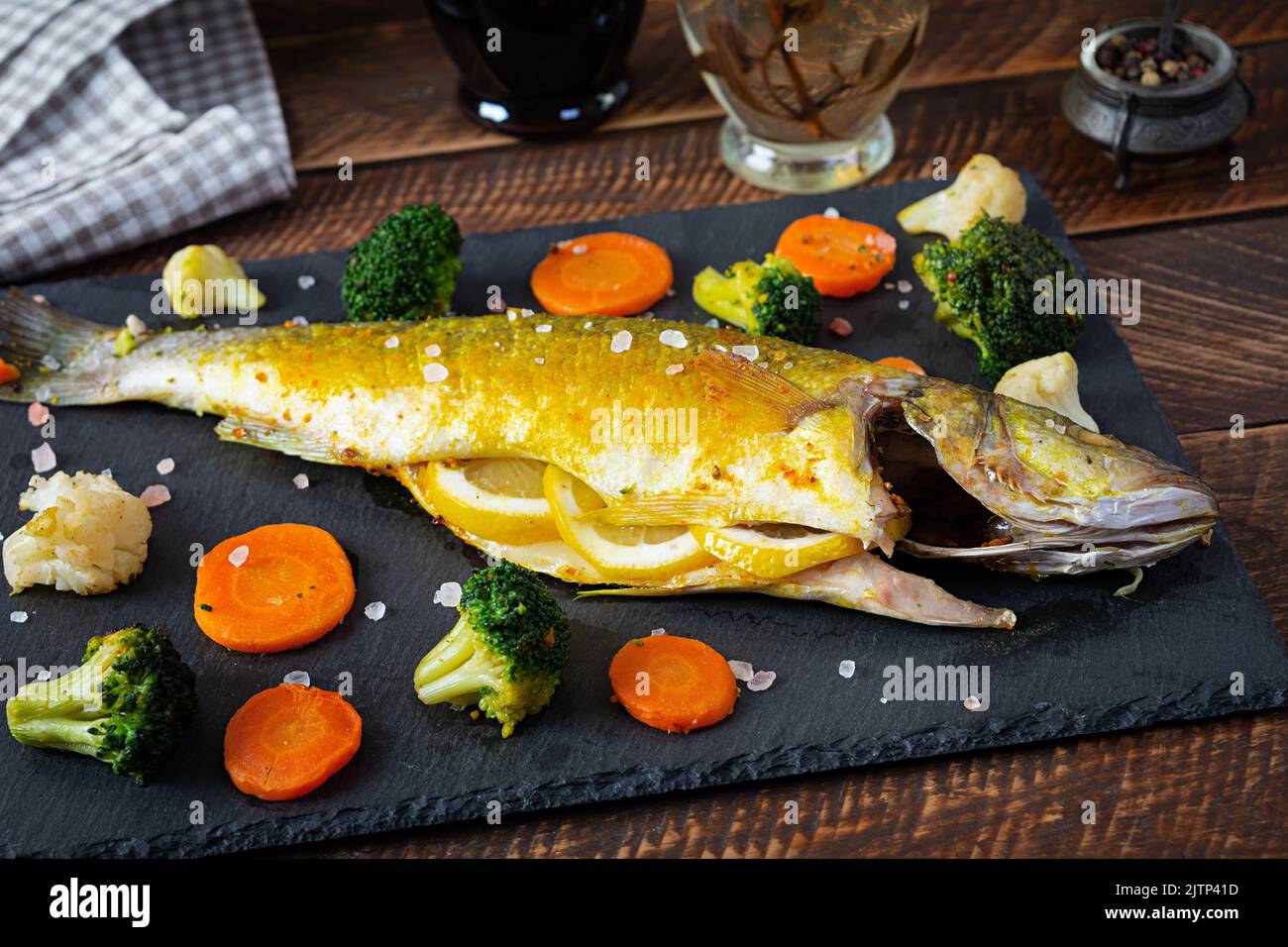 Baked sea bass fish with vegetables and greens on stone plate Stock ...