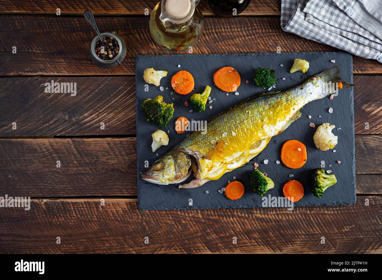 Baked sea bass fish with vegetables and greens on stone plate Stock ...