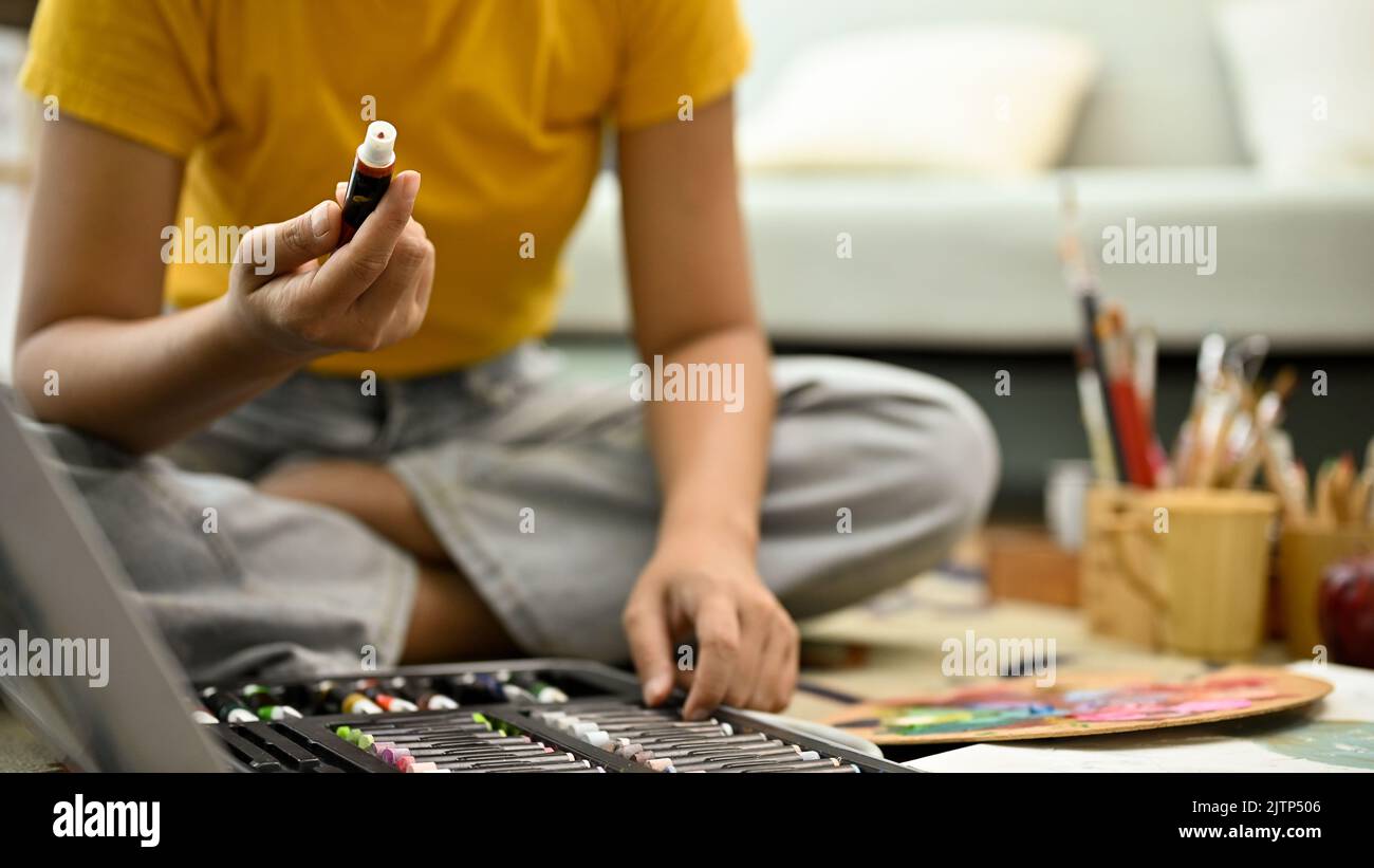 A female student doing her art homework at home, mixing acrylic color ...