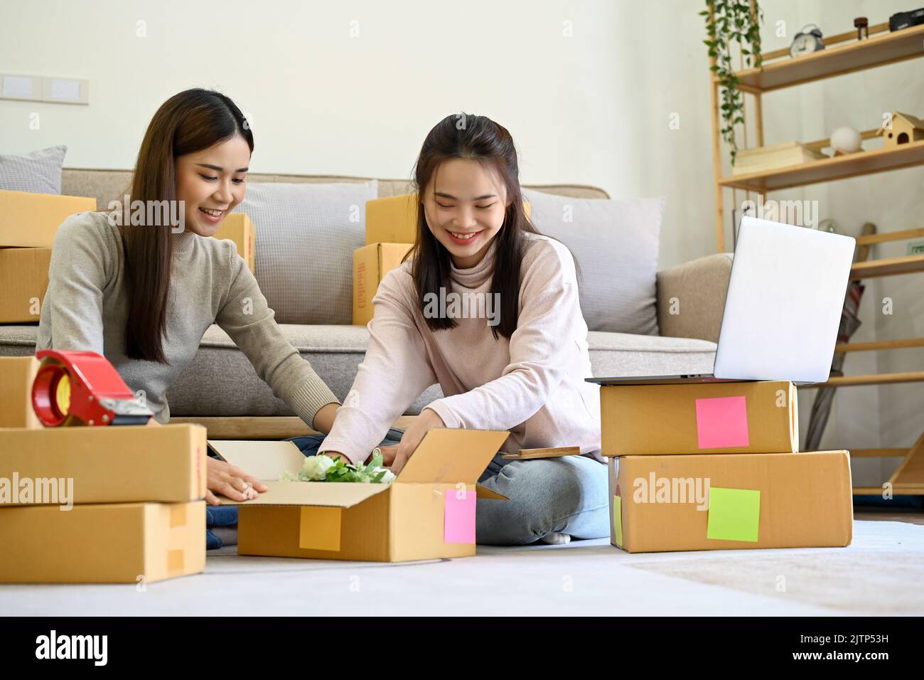 Two pretty young Asian female friends packing a customer's order into a ...