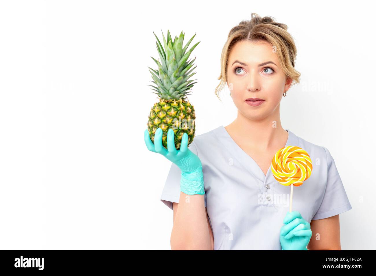 Young caucasian female doctor nutritionist holding fresh pineapple with ...