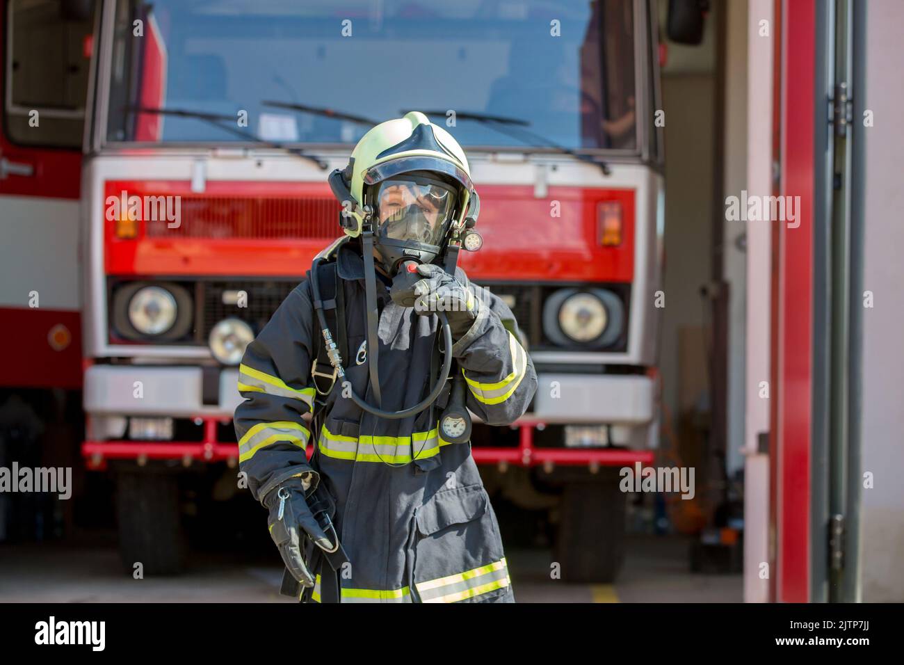 Child, cute boy, dressed in fire fighers cloths in a fire station with ...