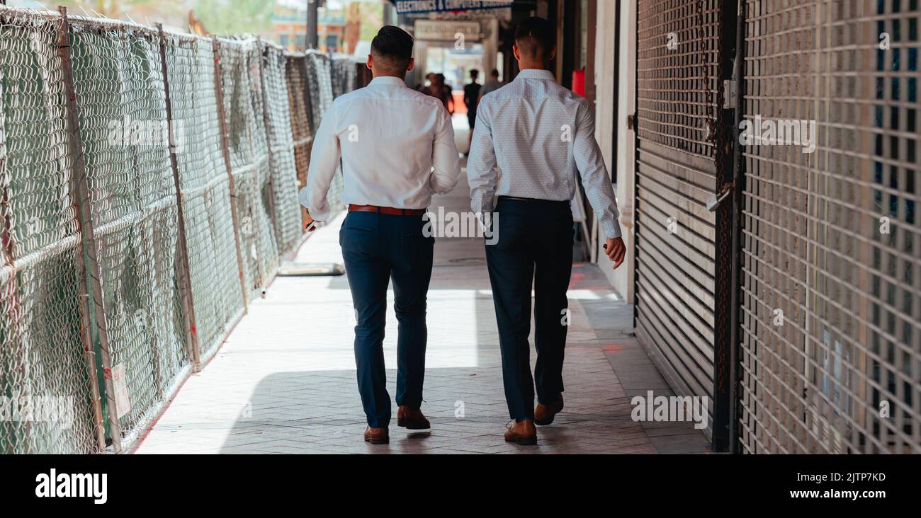A back view of two businessman walking on a sidewalk Stock Photo - Alamy