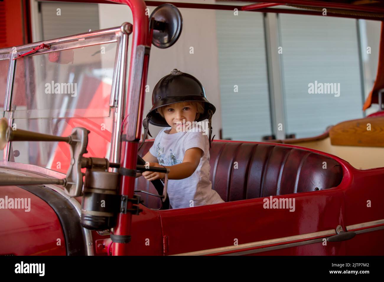 Child, cute boy, dressed in fire fighers cloths in a fire station with ...