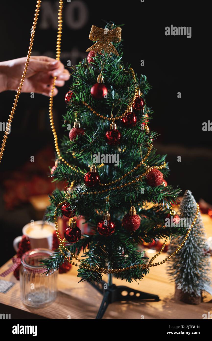 person hand decorating green festive christmas tree at new year eve ...